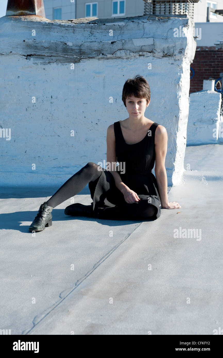 Beautiful young American woman sitting on a roof Stock Photo - Alamy
