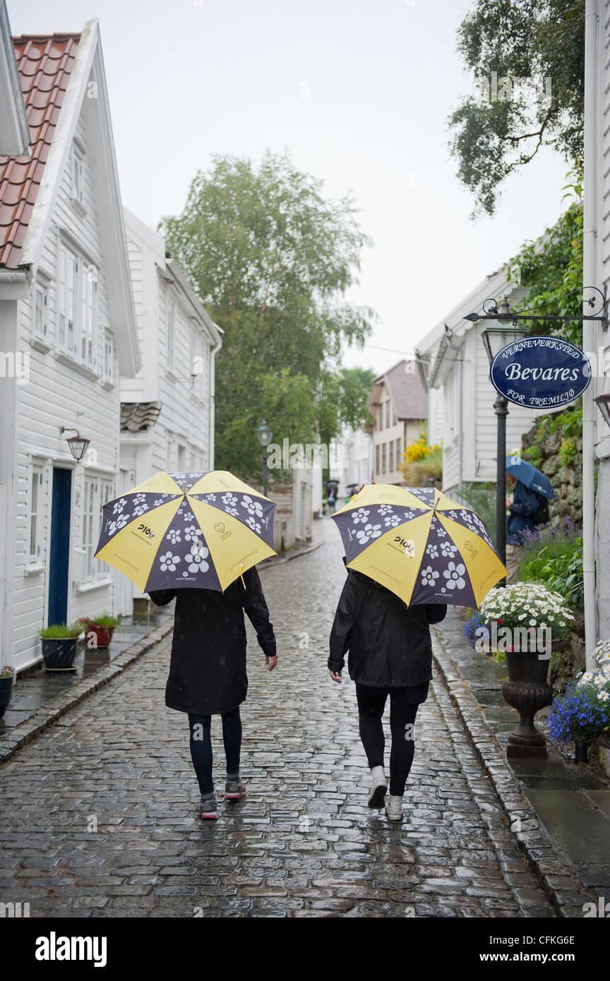 People with umbrellas walking along the streets of the old town of ...