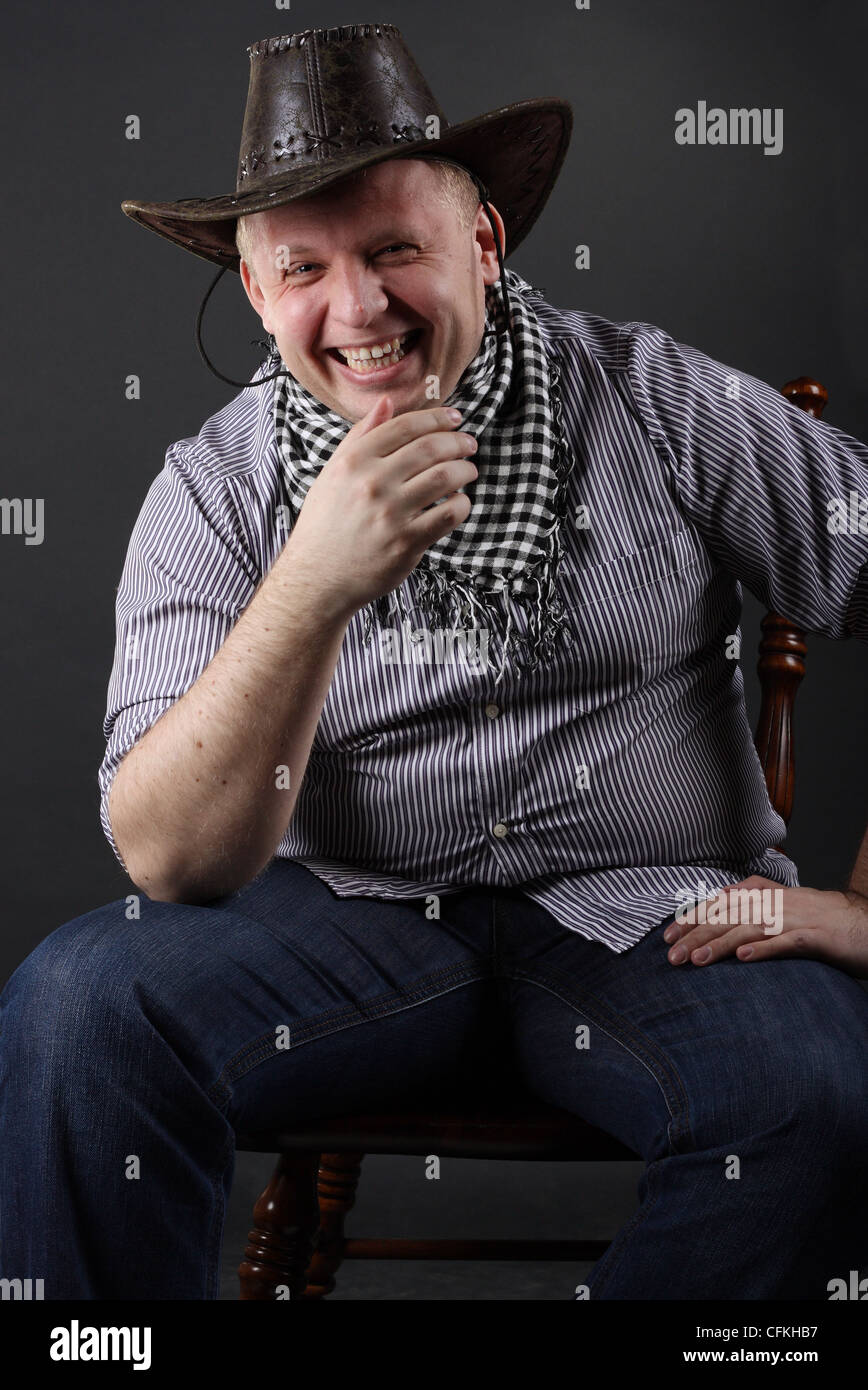 Man in a hat sitting on a chair at dark background Stock Photo - Alamy