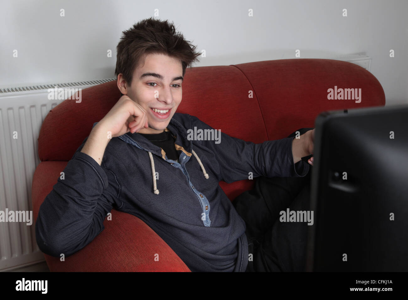 Cheerful young man watching tv alone Stock Photo - Alamy