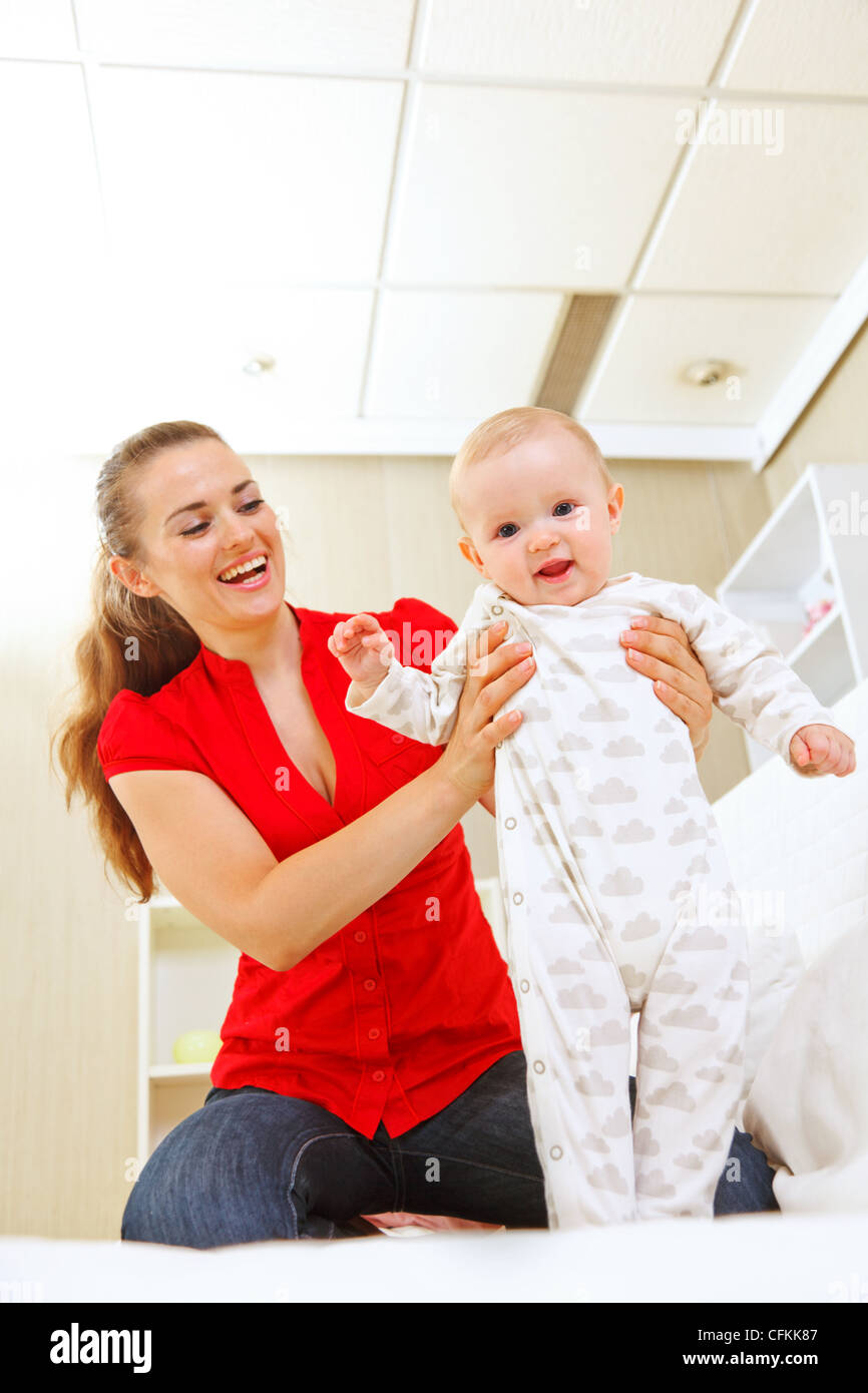 Smiling mother helping baby learn to walk Stock Photo - Alamy