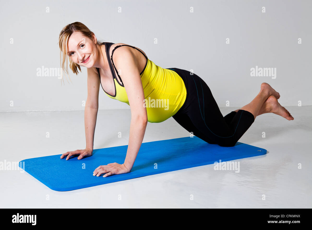 Pregnant woman doing a chest muscle strengthening push-up exercise on a ...
