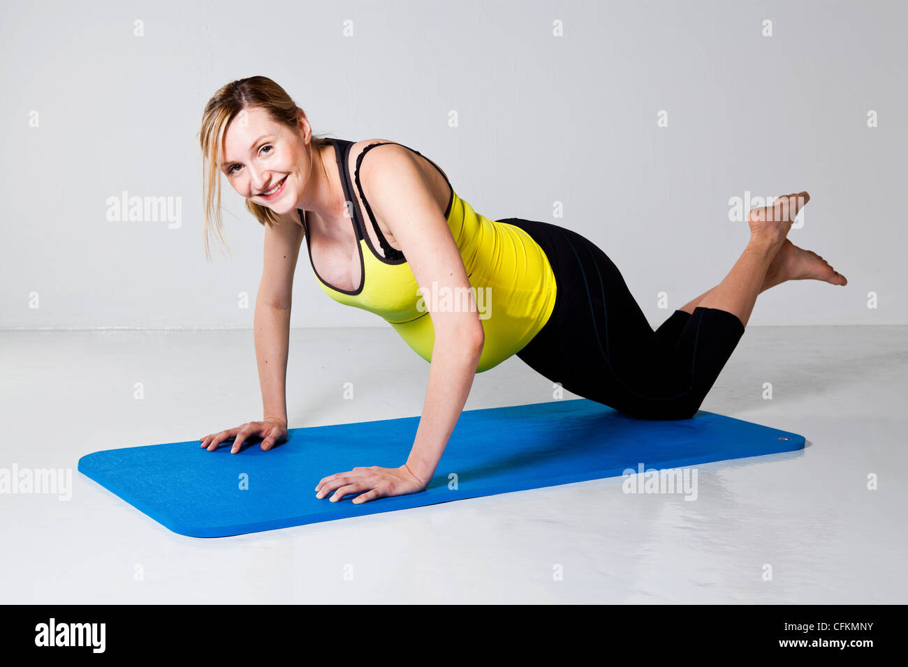 Pregnant woman doing a chest muscle strengthening push-up exercise on a ...