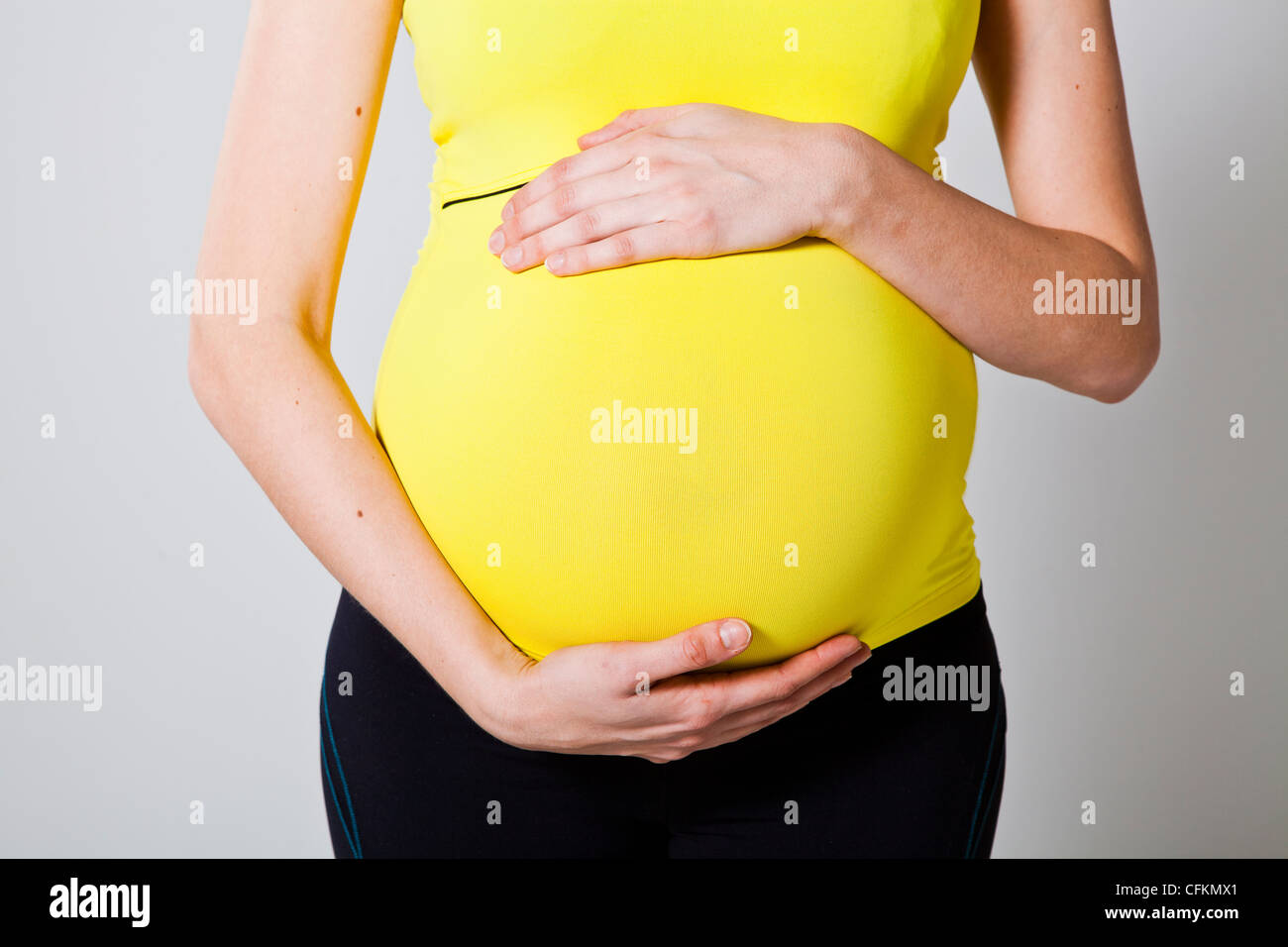 Close-up of pregnant belly with hands on the belly holding Stock Photo ...