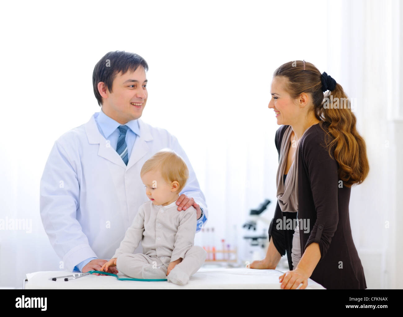 Pediatric doctor talking with mother while baby playing with ...