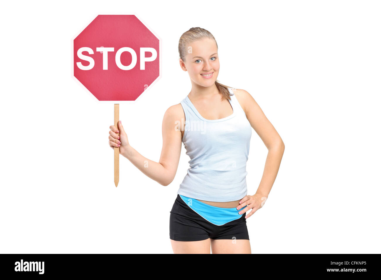 A smiling girl holding a traffic sign stop isolated on white background ...