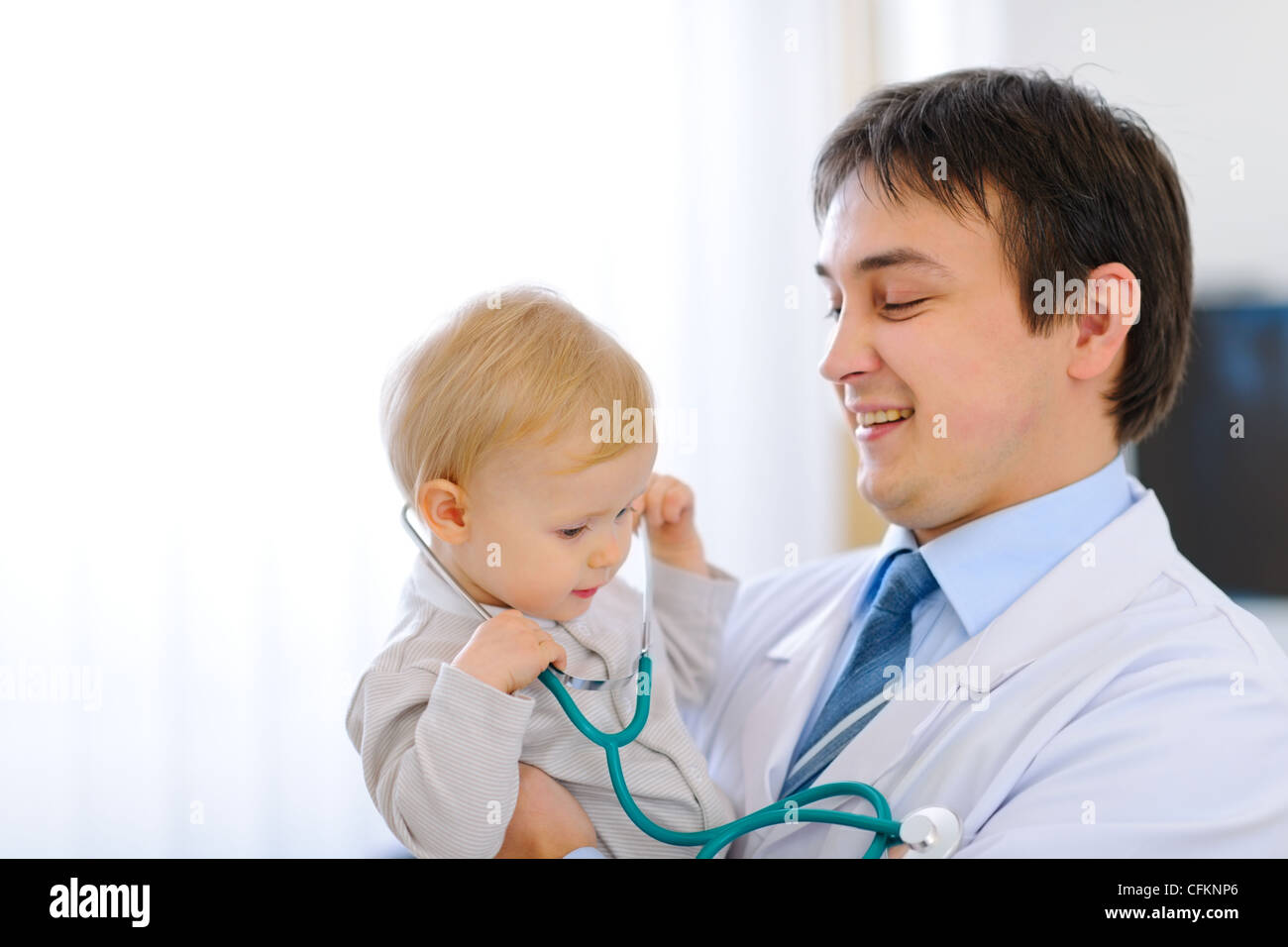Portrait of happy cute baby with stethoscope on hands of pediatrician ...