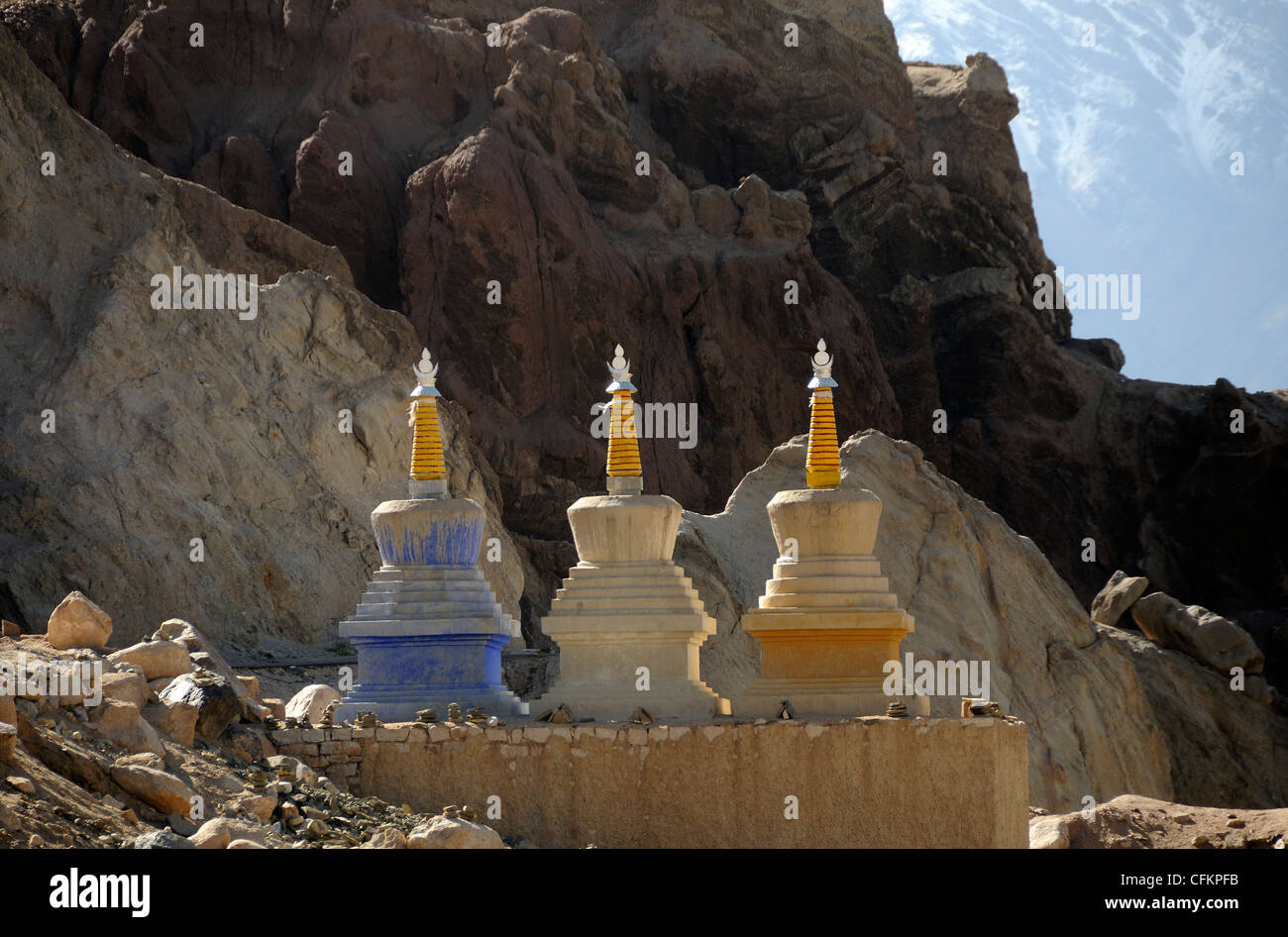 Three coloured chortens with offerings at their bases. Near the ruined ...