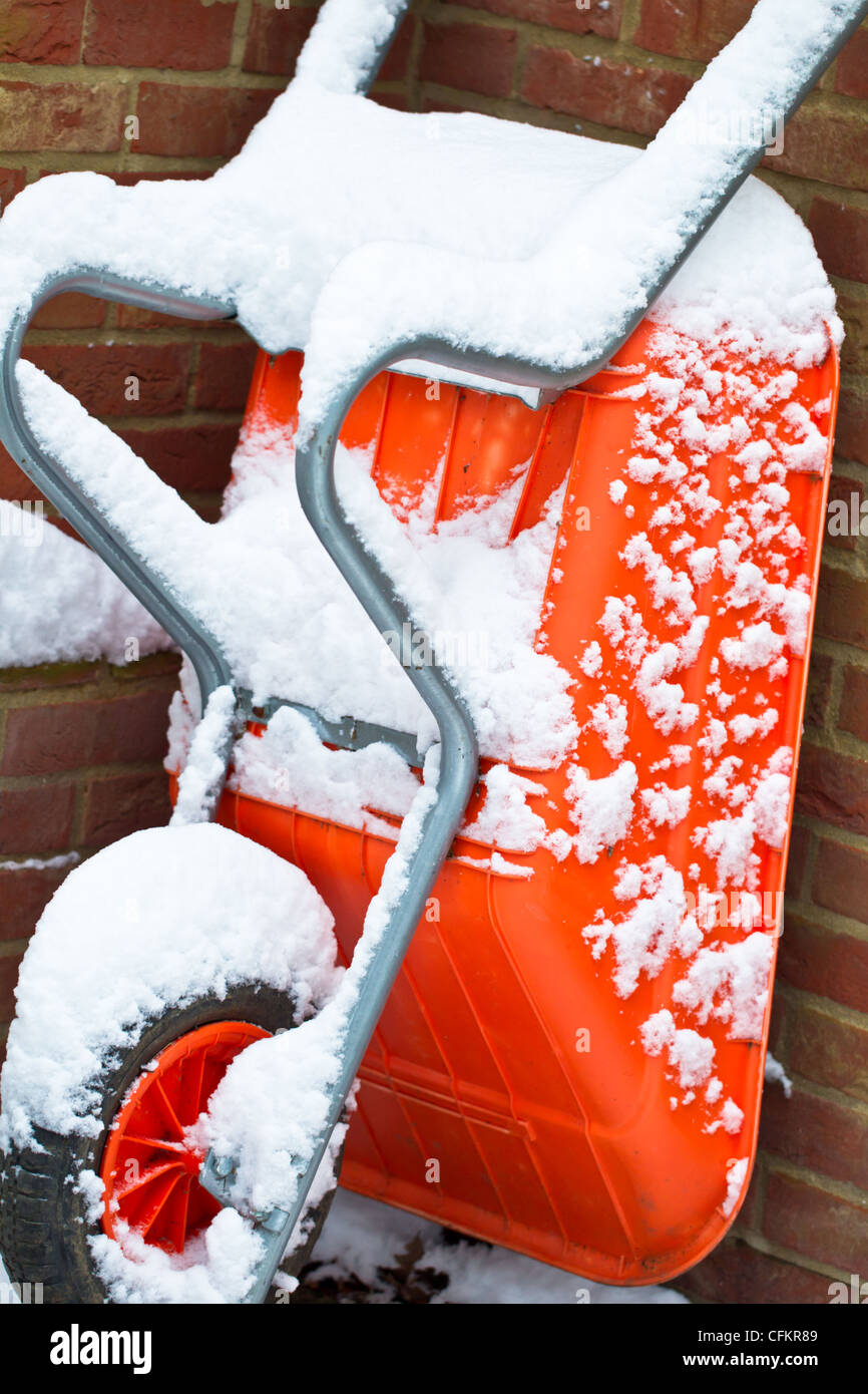 Orange wheelbarrow and snow Stock Photo - Alamy