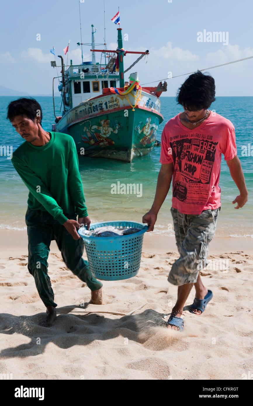 Fishermen unloading fish from colorful fishing boat on a beach in Koh ...