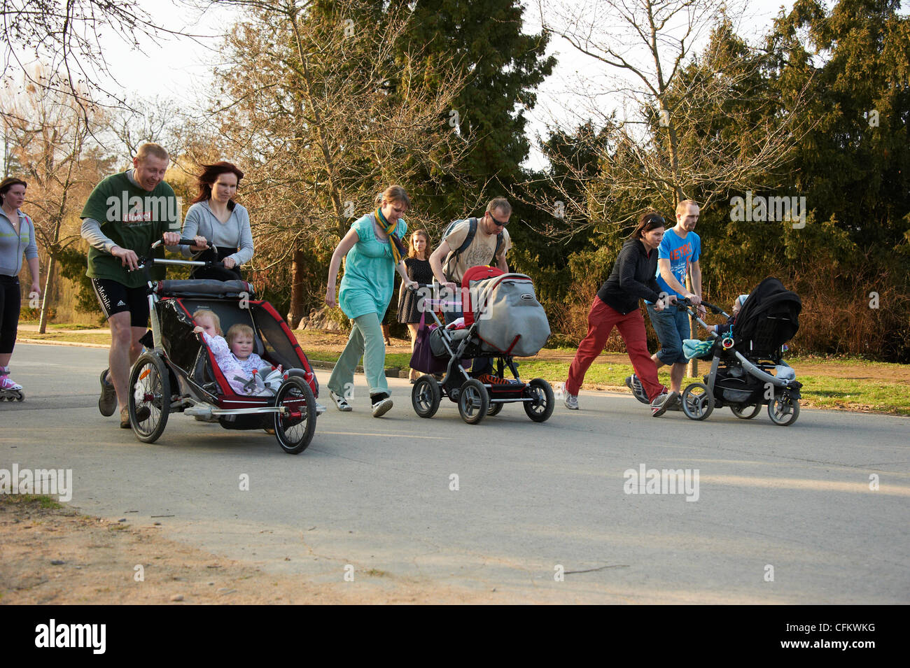 Parents running with baby in stroller in park. Strollering is ...