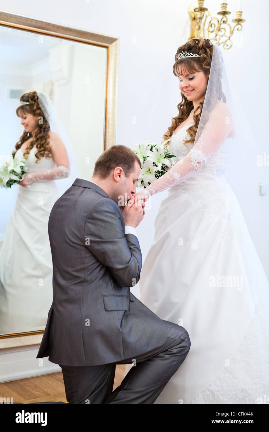 Young wedding Caucasian Russian couple. Bridegroom standing on kneels ...