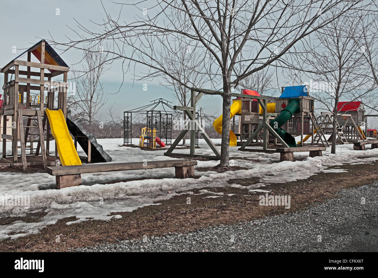 Early spring. We see a park with rustic wooden playground structures ...