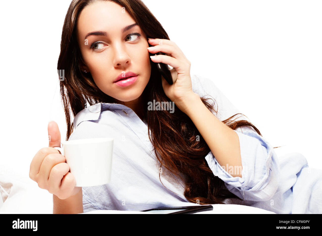 beautiful woman in bed holding coffee while calling with her phone on ...