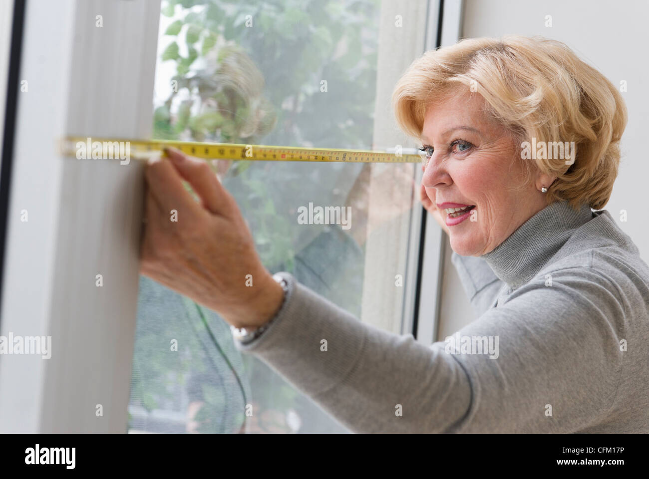 USA, New Jersey, Jersey City, Senior woman measuring window Stock Photo ...