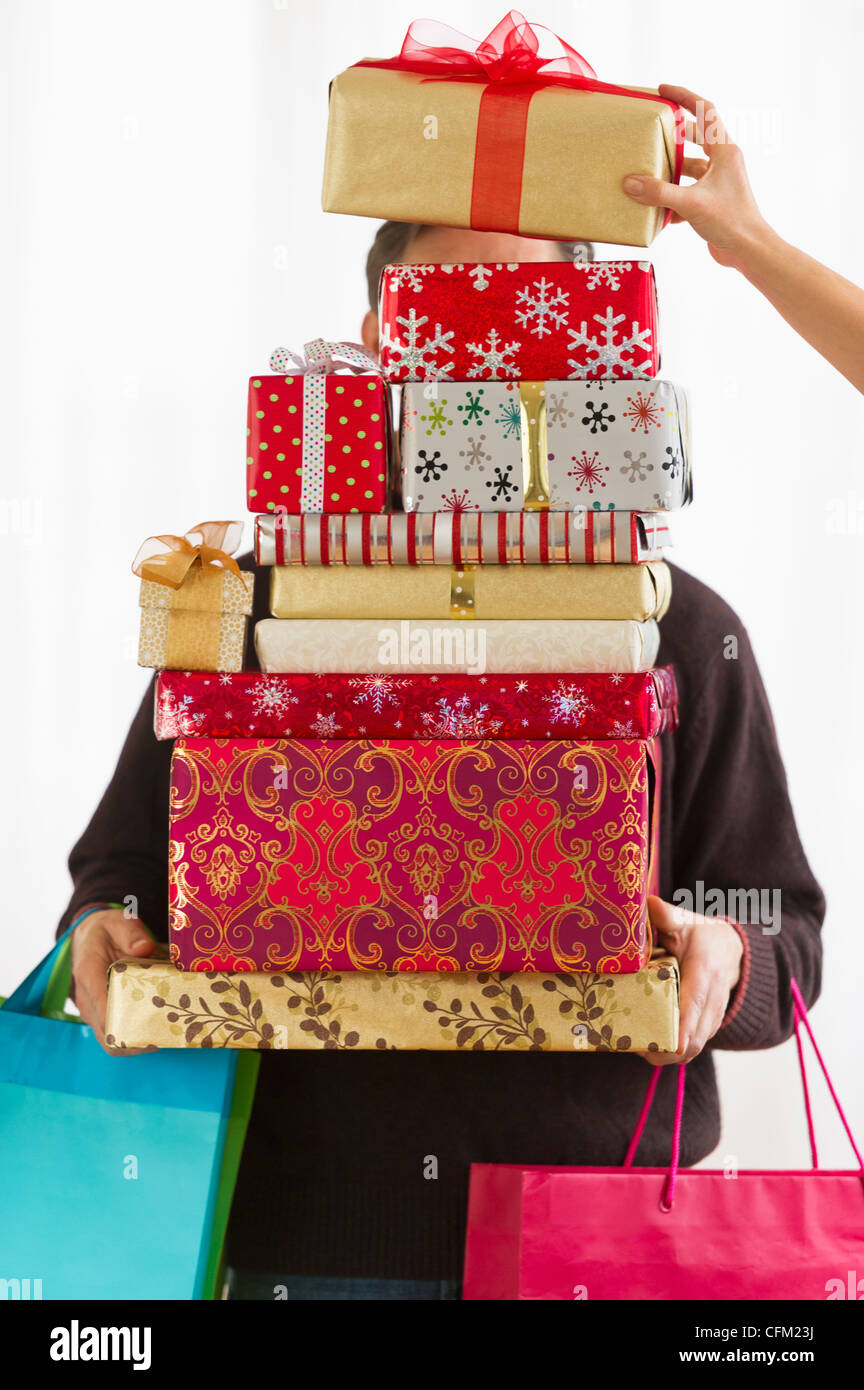 Man carrying stack of Christmas presents, studio shot Stock Photo - Alamy