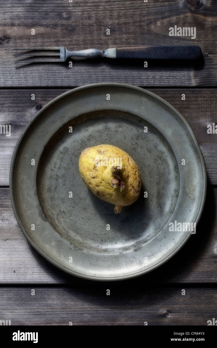old, shriveled potatoes with sprouts on antique plate with fork Stock ...