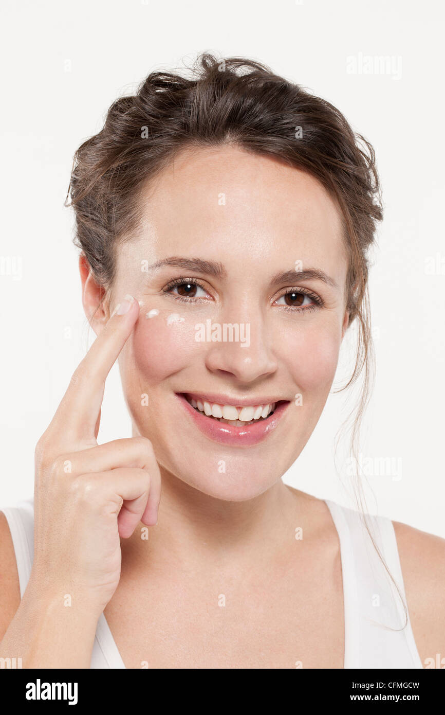 Portrait of woman applying face cream, studio shot Stock Photo - Alamy