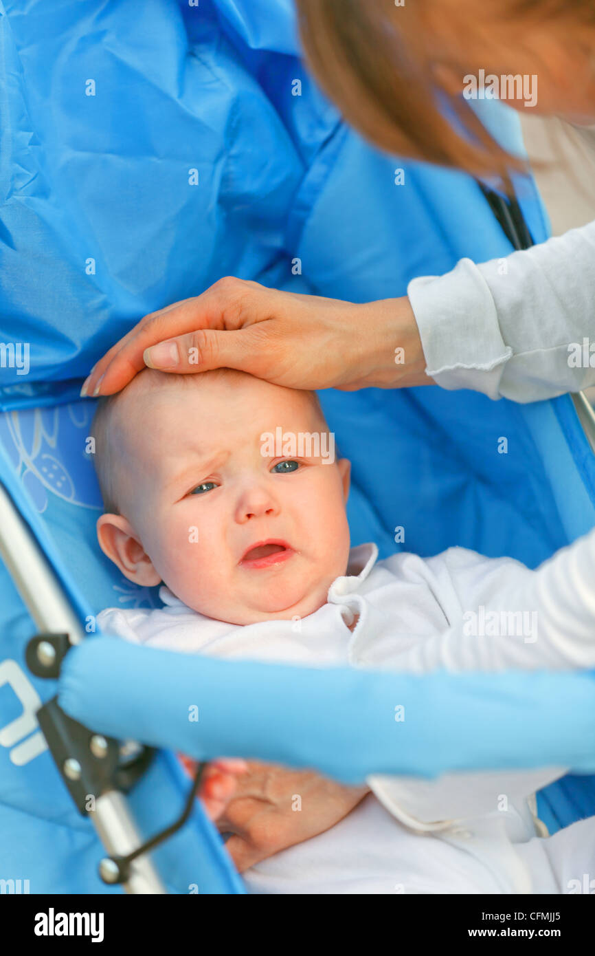 Caring mother soothing sitting in stroller crying baby girl Stock Photo ...
