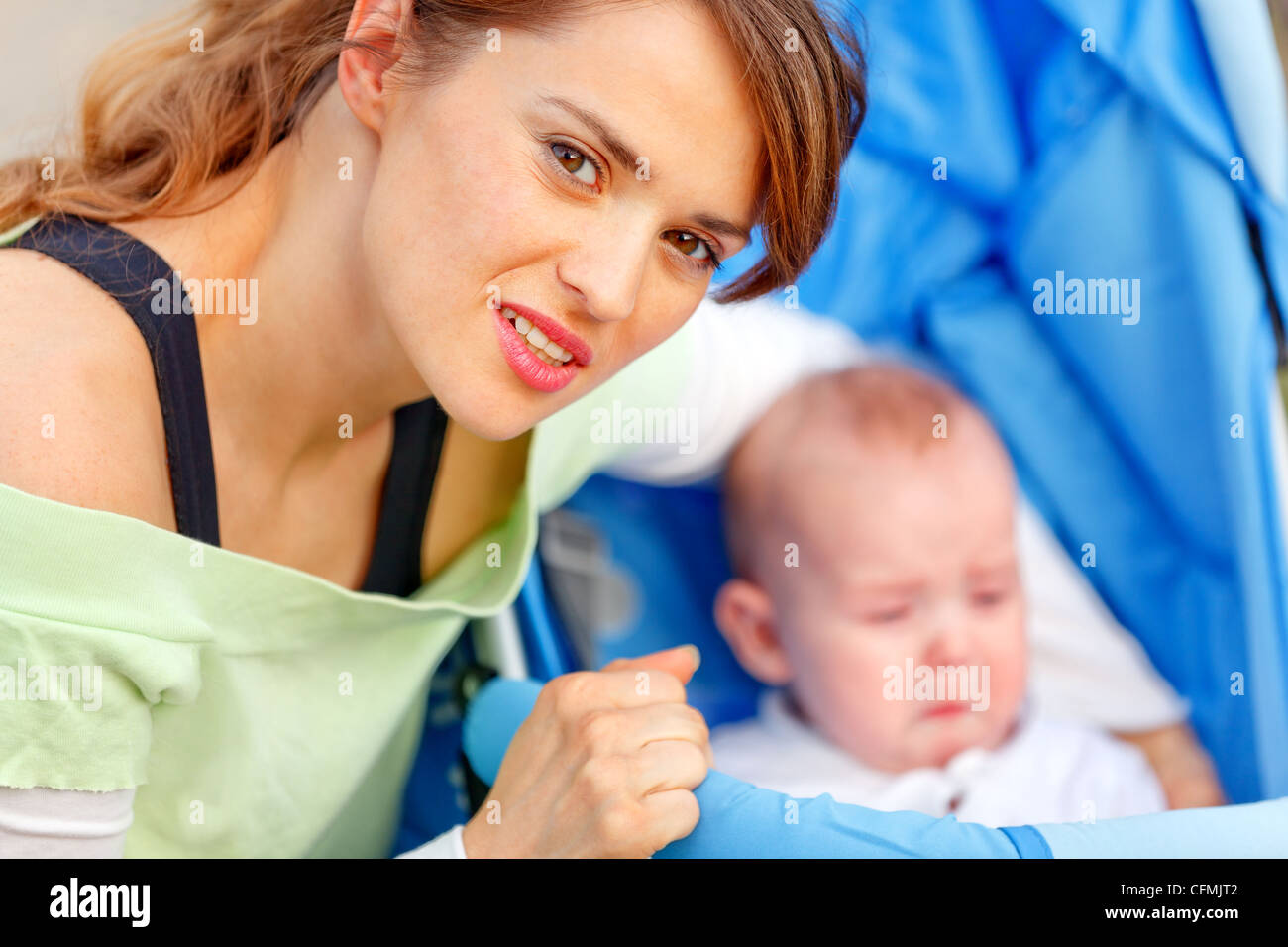 Caring young mother hugging sitting in stroller crying baby Stock Photo ...