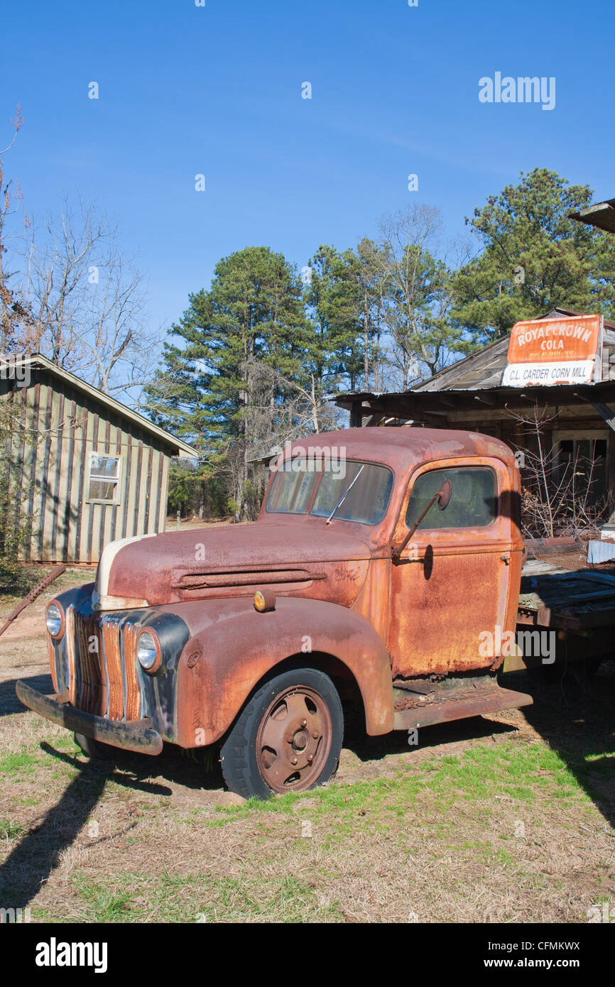 An old rusty antique truck sits beside an old store from the same era ...