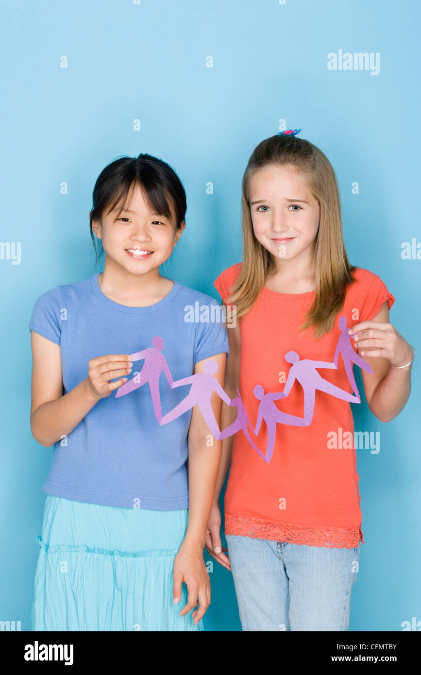 Studio shot portrait of two teenage girls holding paper chain, three ...
