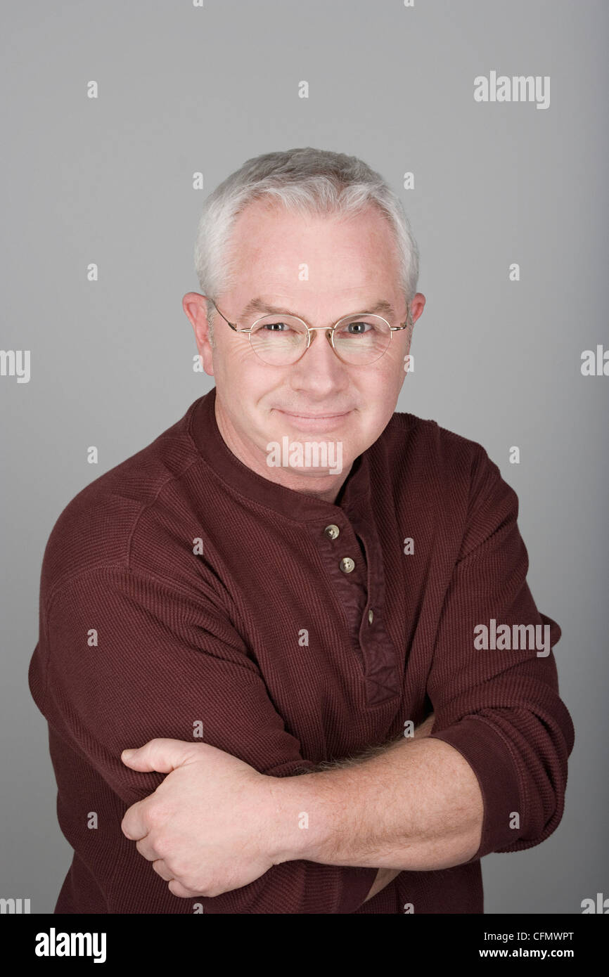 Studio shot portrait of senior man with arms crossed, head and ...