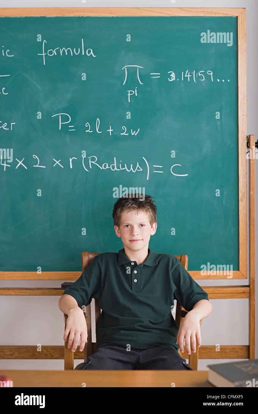 USA, California, Los Angeles, boy sitting in teachers chair, blackboard ...