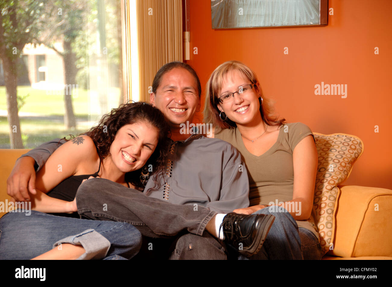 Friends Sitting on Couch Hugging Stock Photo - Alamy