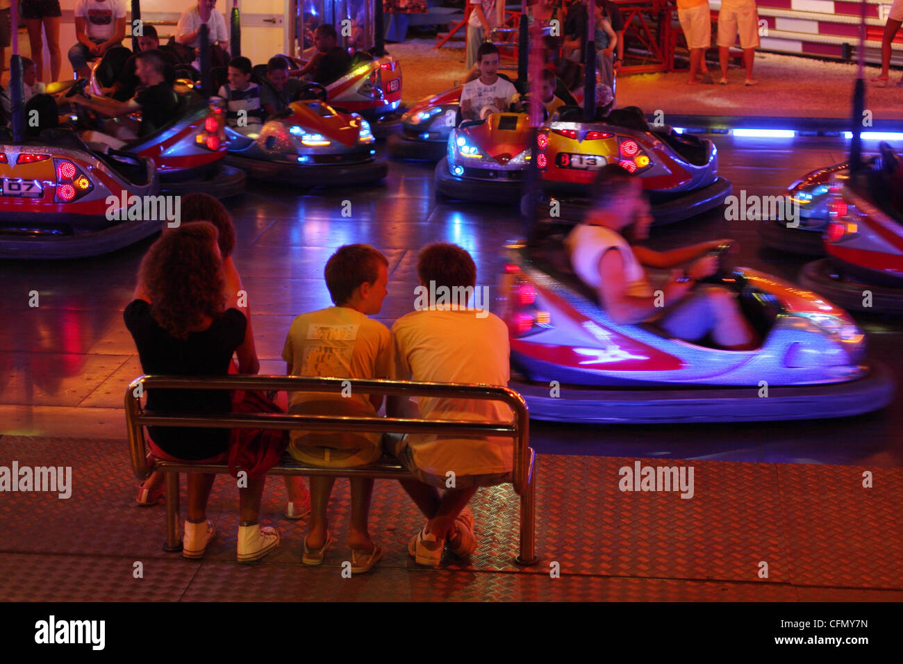 Young people ride in a bumper car and rest on the bench. Budva ...