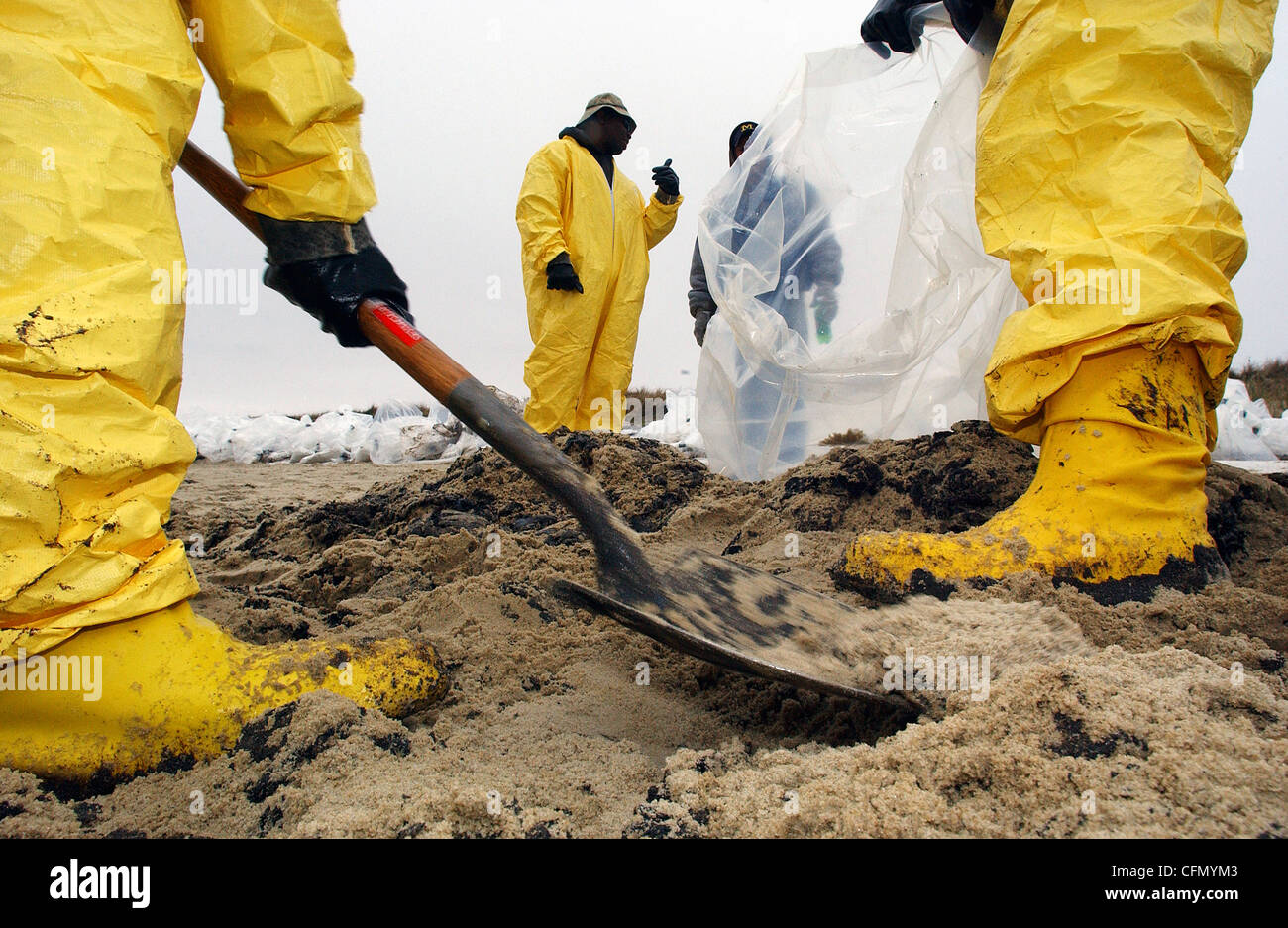 Men from an environmental clean-up company work to remove oil ...