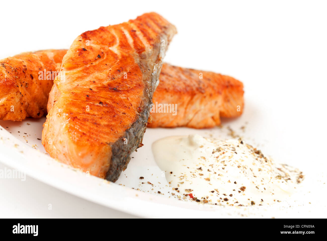Fried salmon fillets with sauce on white plate Stock Photo - Alamy