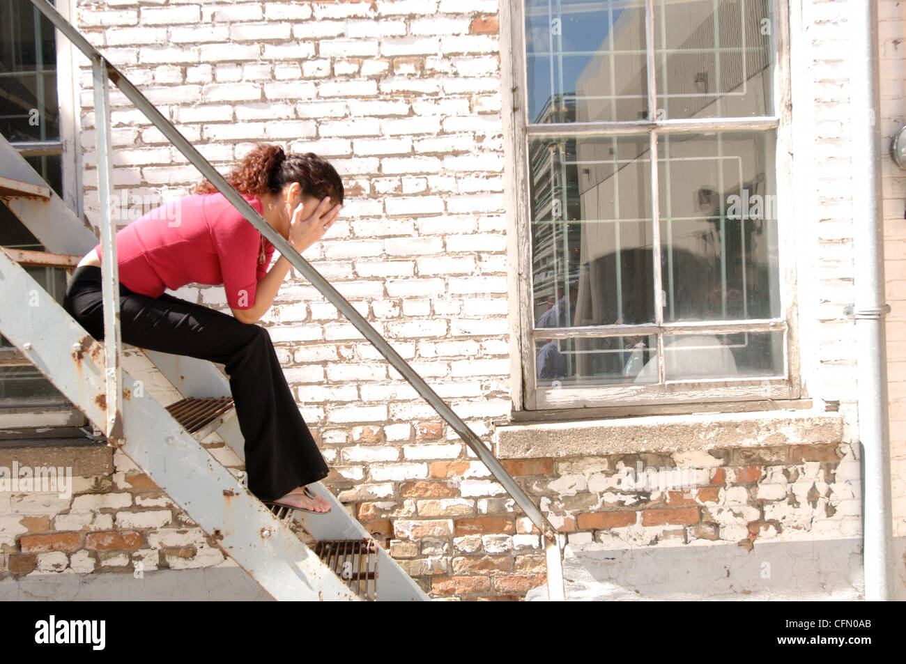 Woman Sitting on Fire Escape with Face in Hands Stock Photo - Alamy