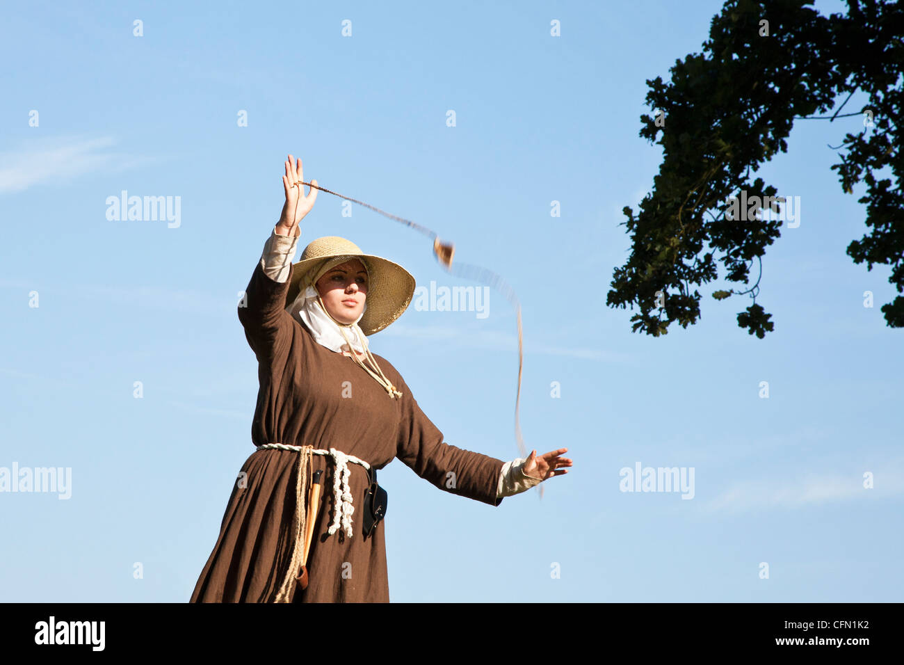 Young woman in medieval costume using slingshot at living history fare ...