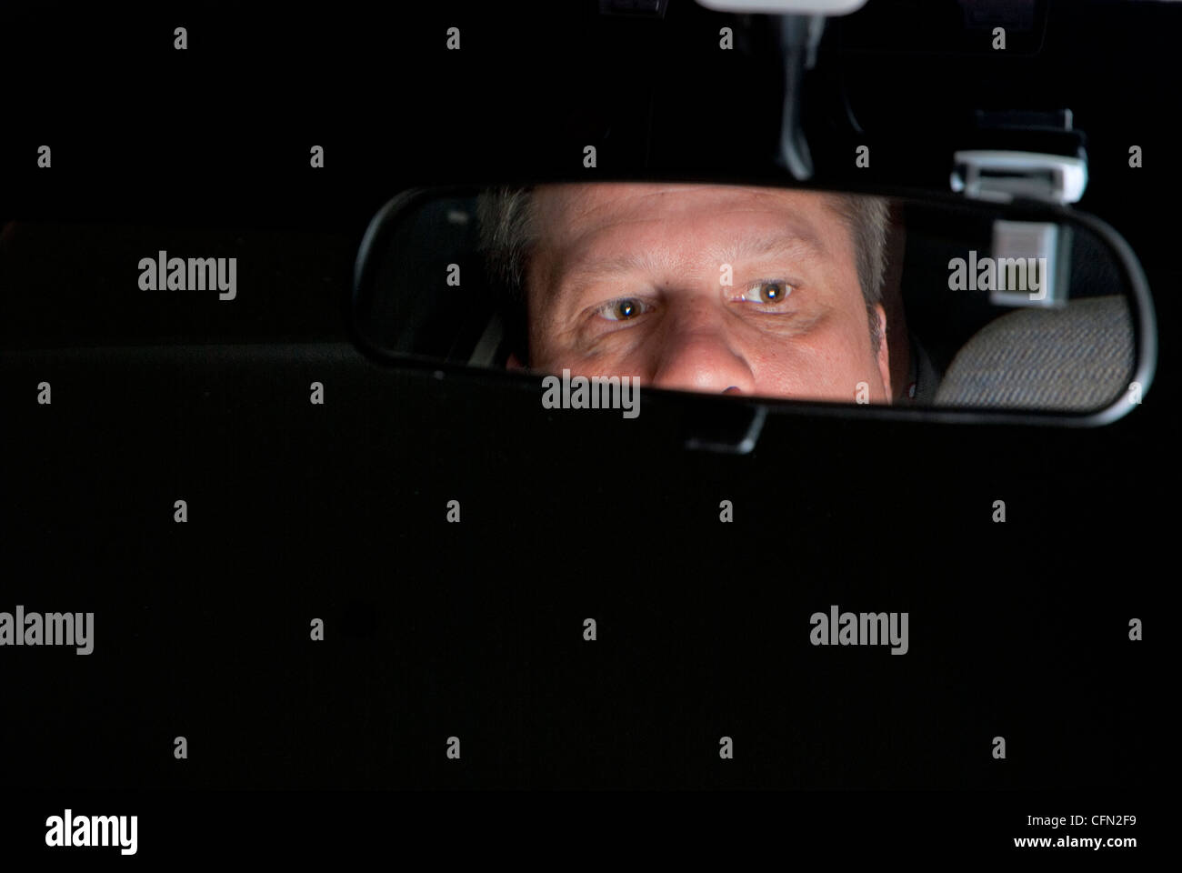 Driver looks in a cars rear view mirror Stock Photo - Alamy