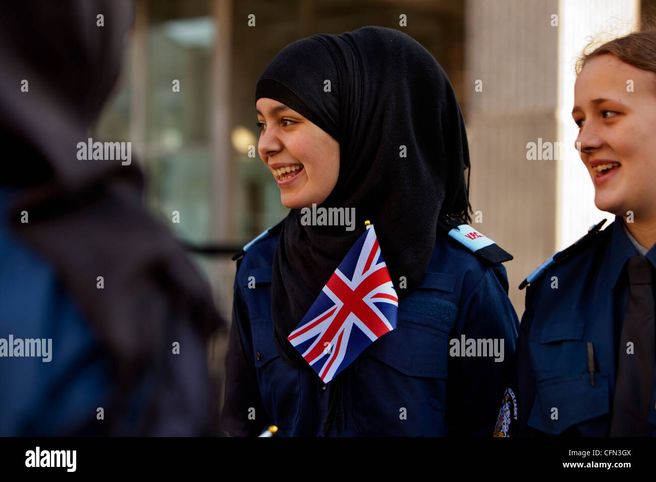 Volunteer Police Cadets with Union jack flags watching an army parade ...