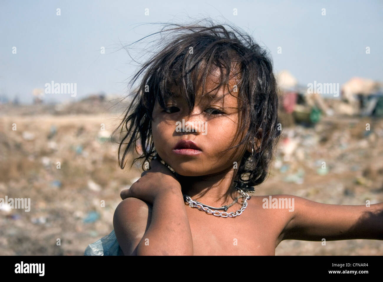 A young child laborer girl is searching for recyclable material at the ...