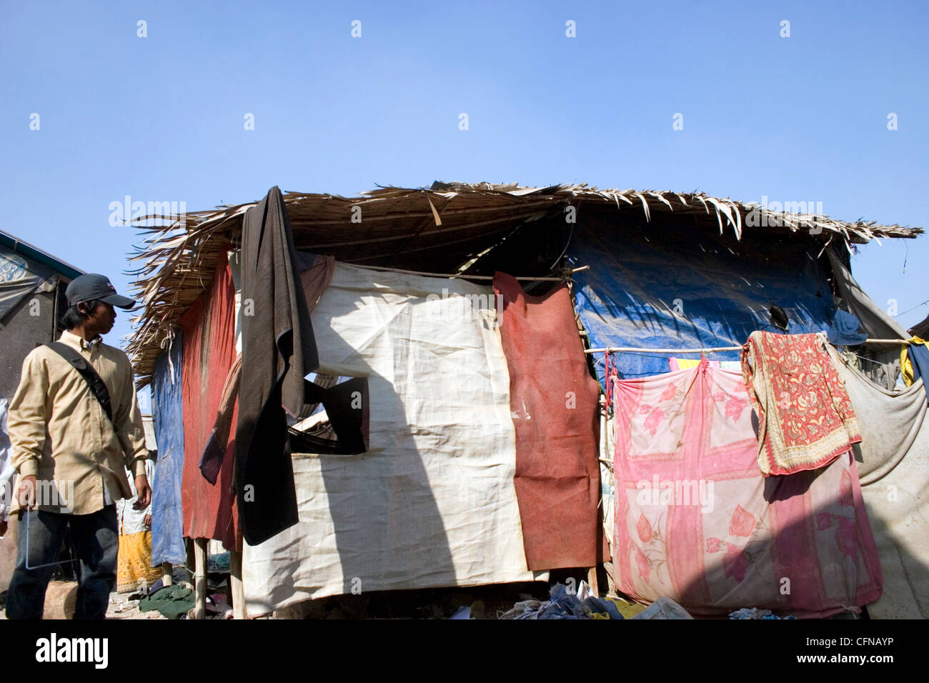 A man is walking past wooden, plastic and canvas shacks near the toxic ...