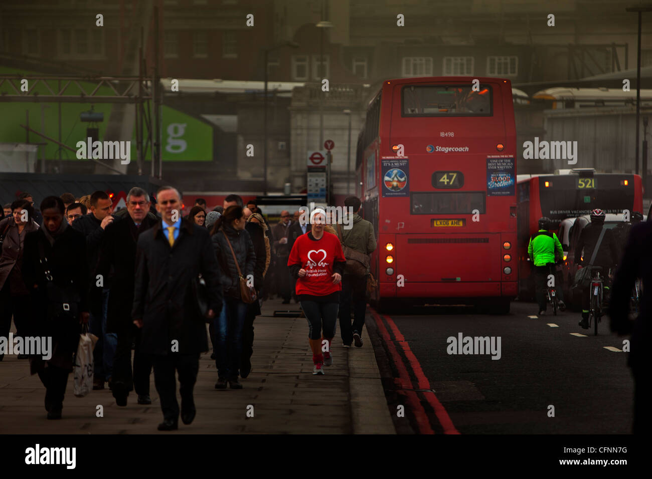 Commuters and busy traffic crossing London Bridge on a smoggy morning ...