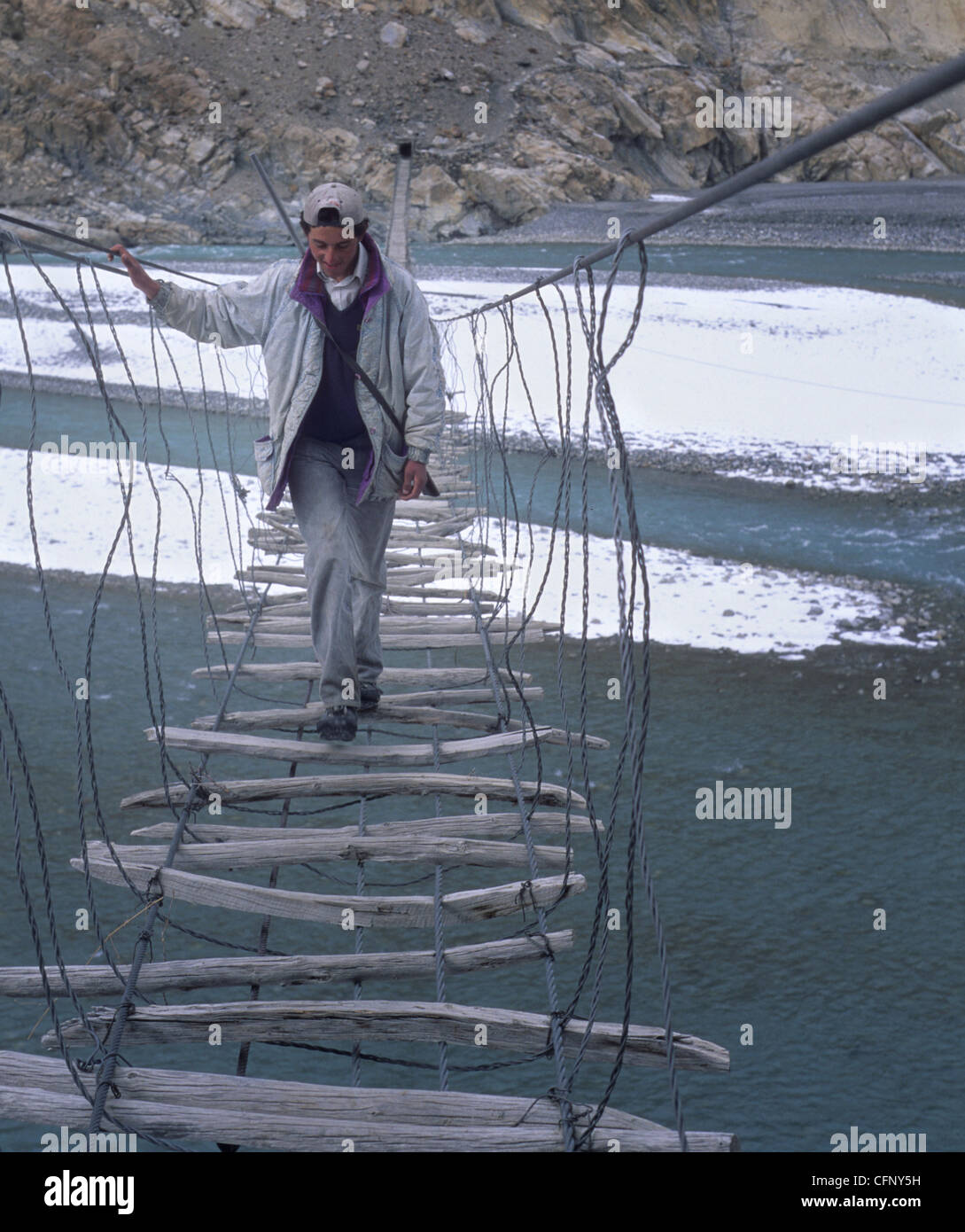 Man crossing the Hussaini bridge in Passu, old suspension bridge, above ...