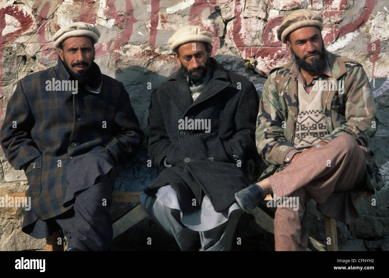 Portrait of three Pakistani men sitting on a bench in the village of ...