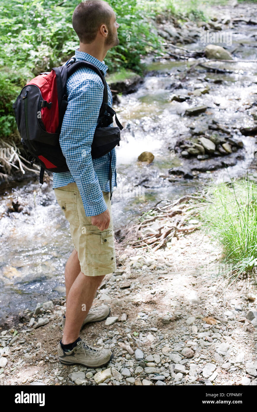 Man hiking along stream in woods Stock Photo - Alamy