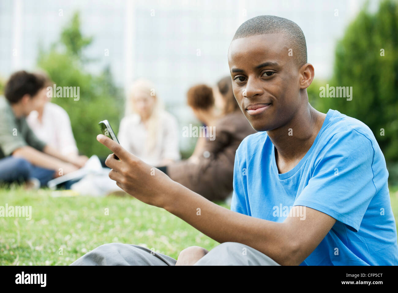 Young man with cell phone, people in background, portrait Stock Photo ...