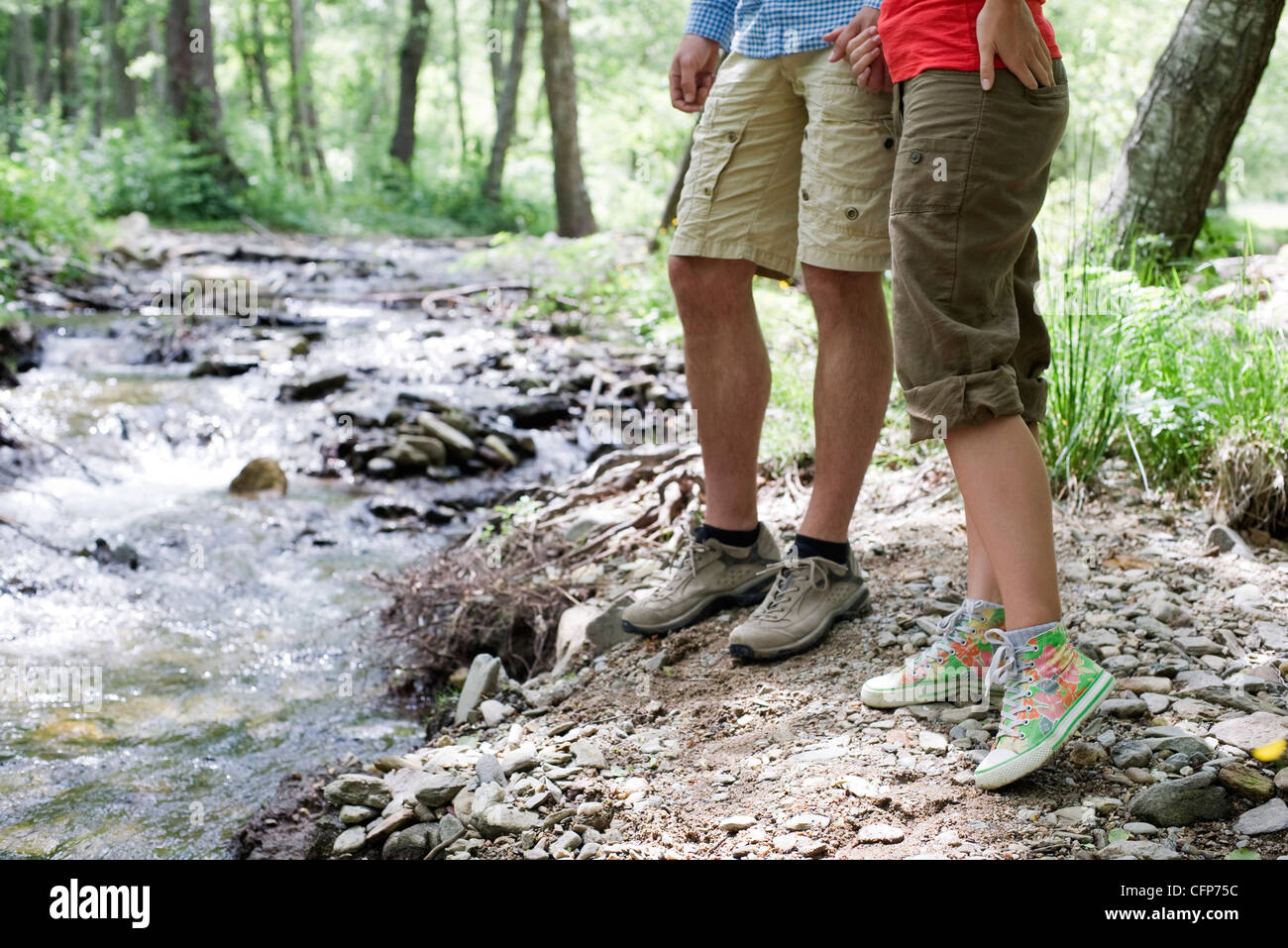 Couple hiking along stream in woods, low section Stock Photo - Alamy