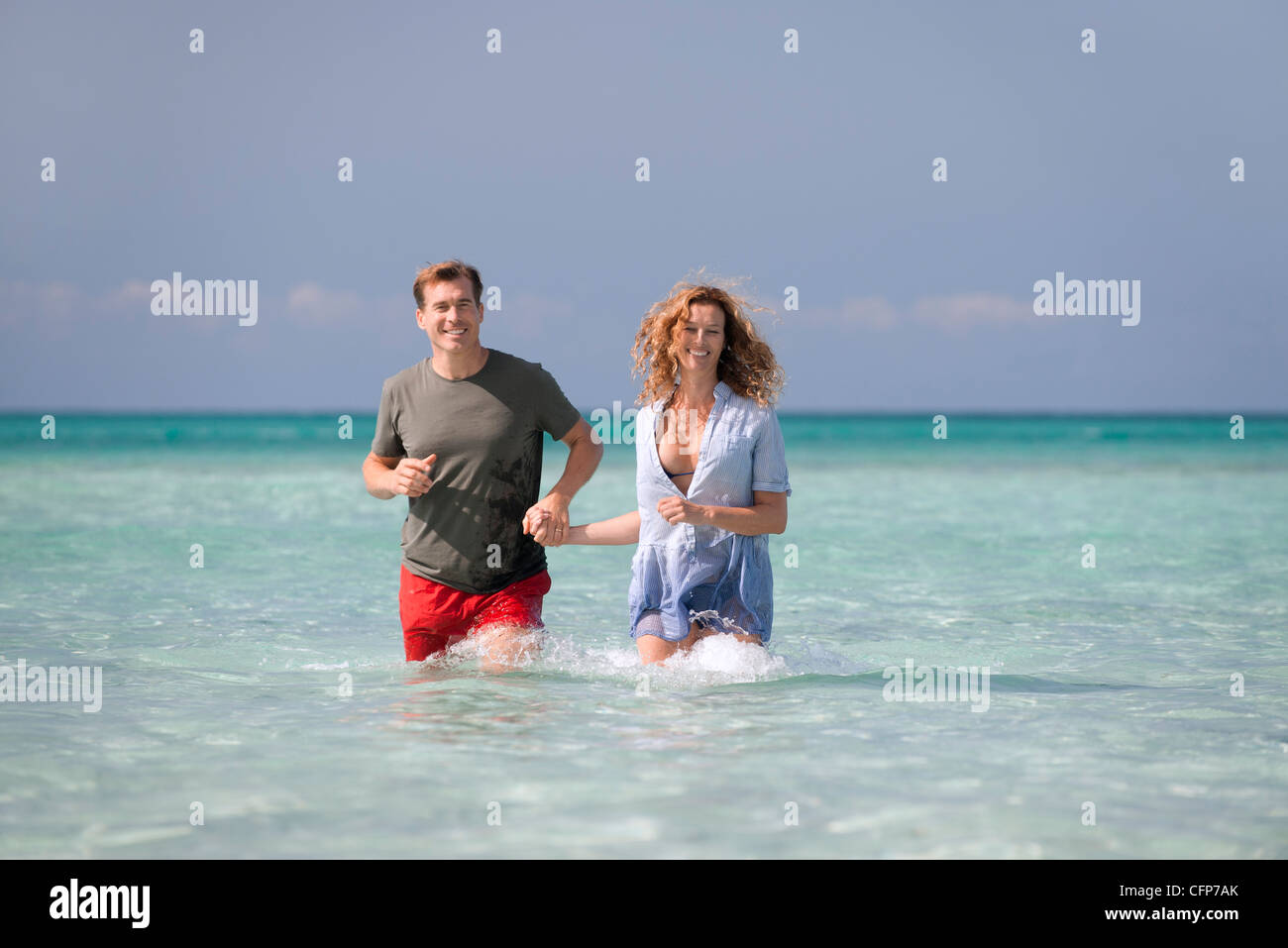 Couple standing knee deep in water, holding hands Stock Photo - Alamy