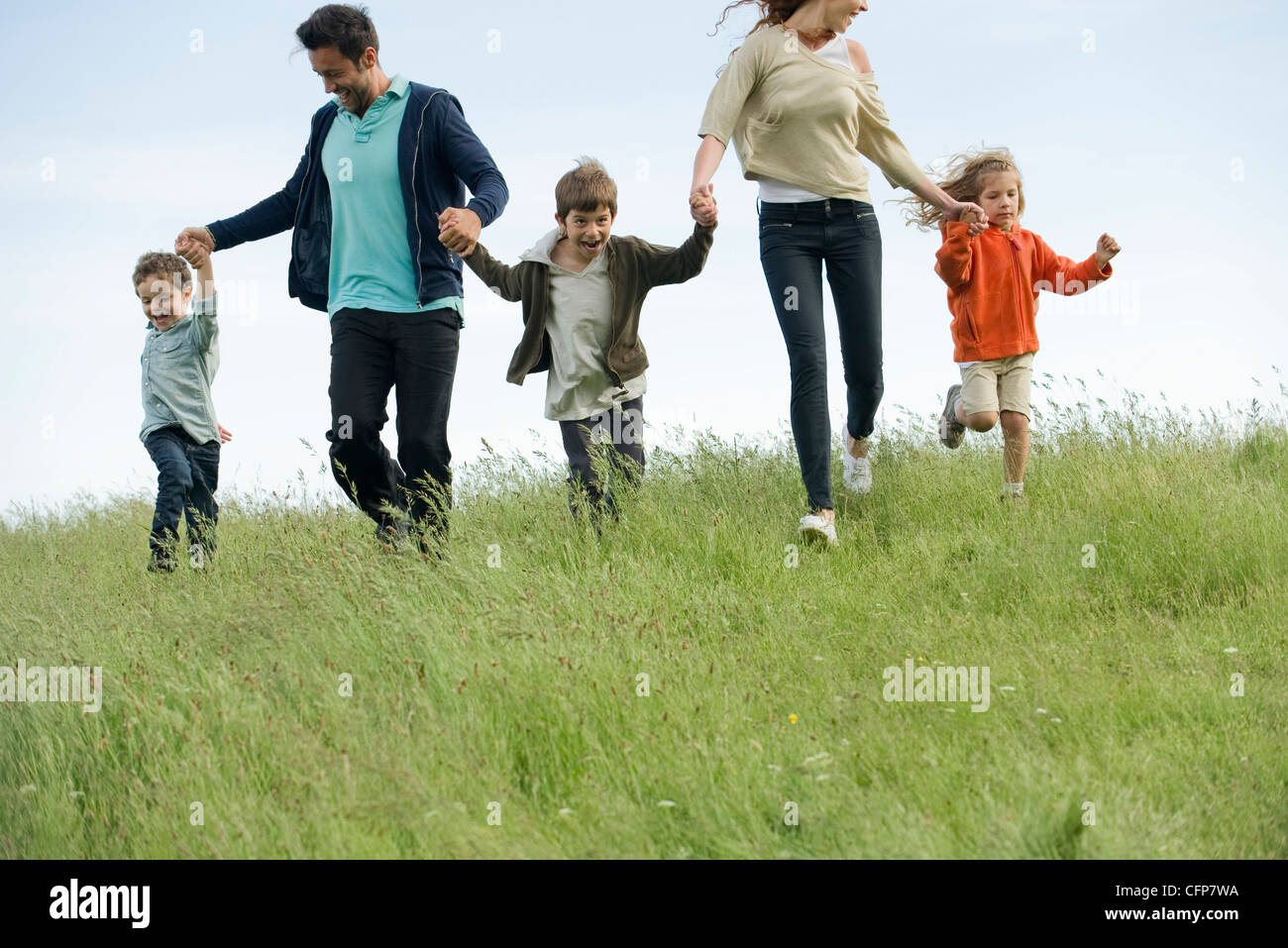 Family running hand in hand in field Stock Photo - Alamy