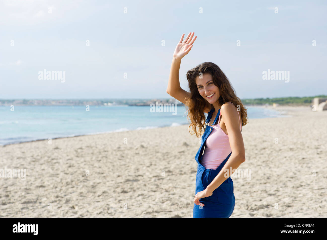 Young woman at the beach, smiling and waving at camera Stock Photo - Alamy