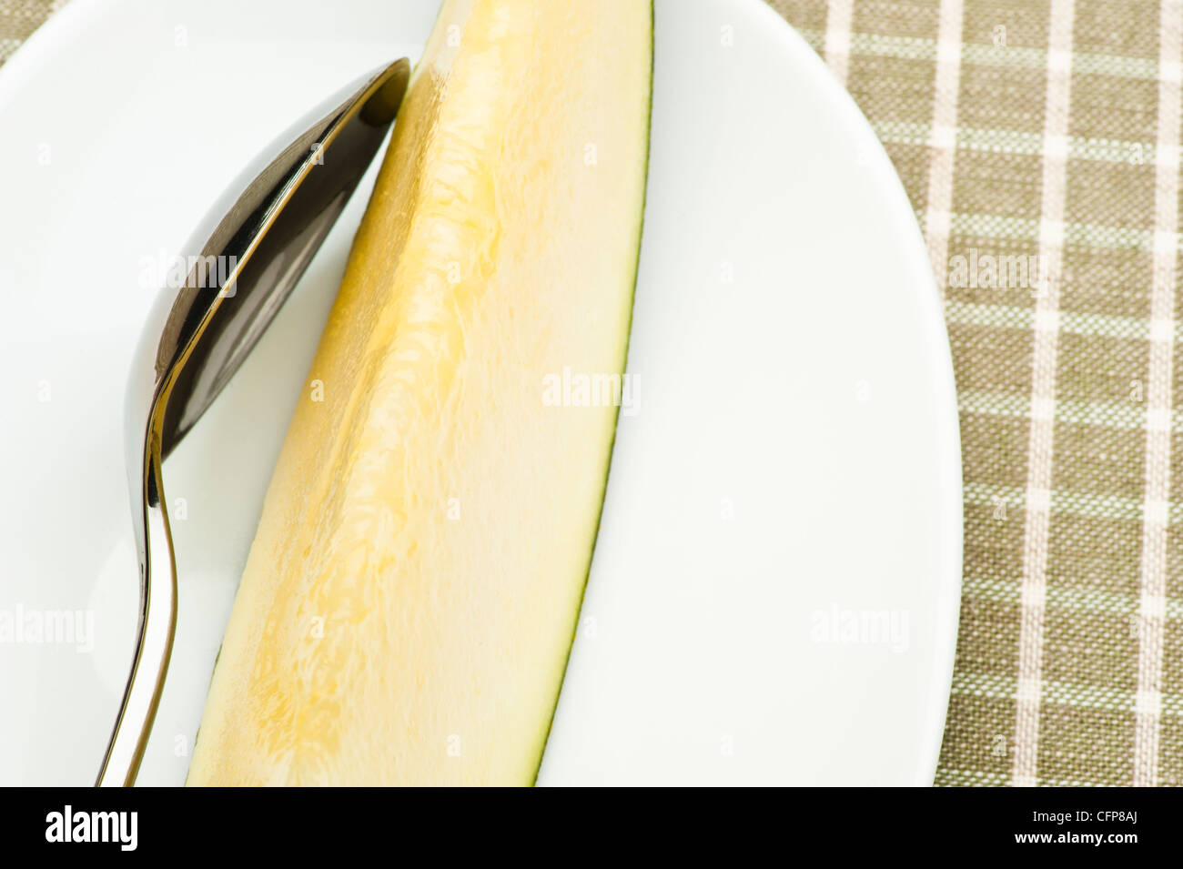 Slice of melon and spoon on a white plate Stock Photo - Alamy