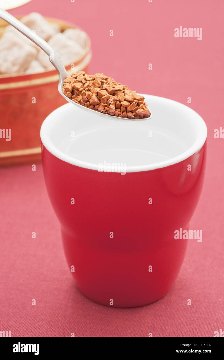 Spoon with instant coffee and cup filled with hot water Stock Photo - Alamy