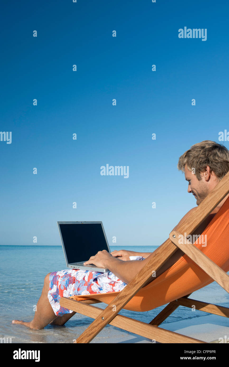 Young man using laptop on beach Stock Photo - Alamy